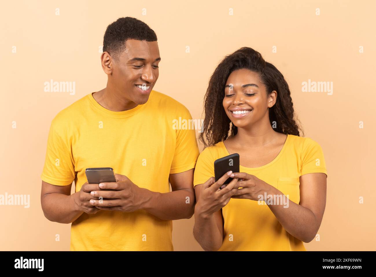 Happy young african american couple using smartphones, lady showing her ...