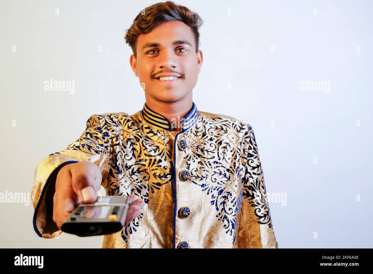indian man in ethnic wear holding remote control Stock Photo - Alamy