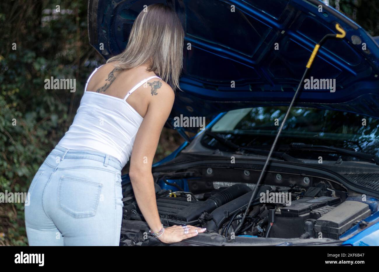 Beautiful woman leaning over looking into the engine compartment of a ...