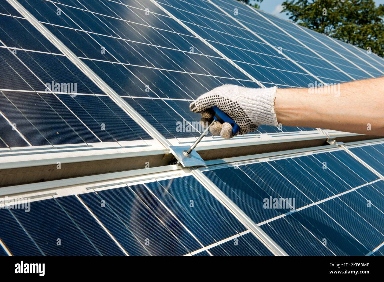 A worker's hand screws solar panels onto a roof in the sun Stock Photo ...