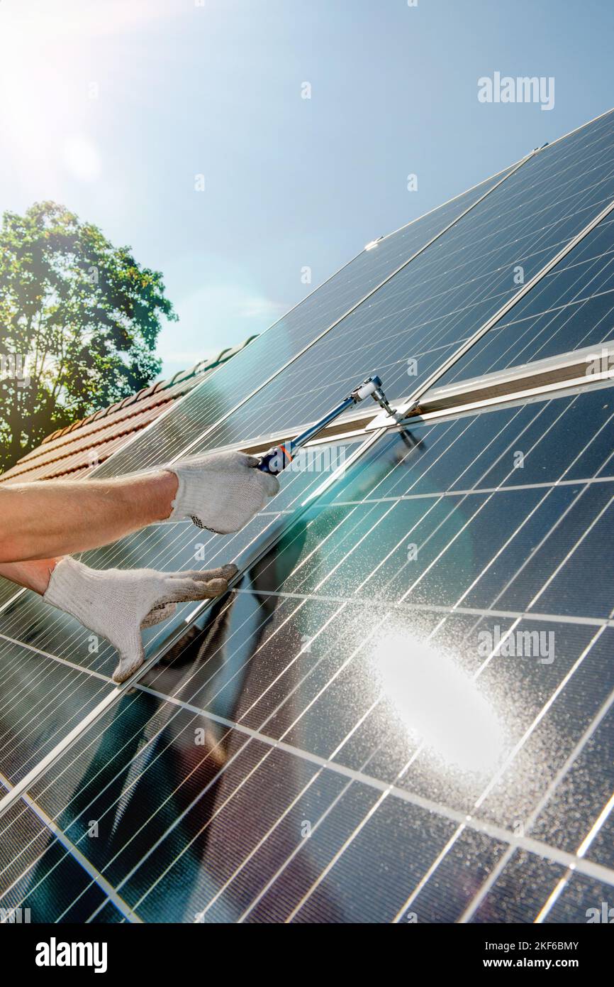 The hand of a worker screws solar panels with beautiful sun reflections ...