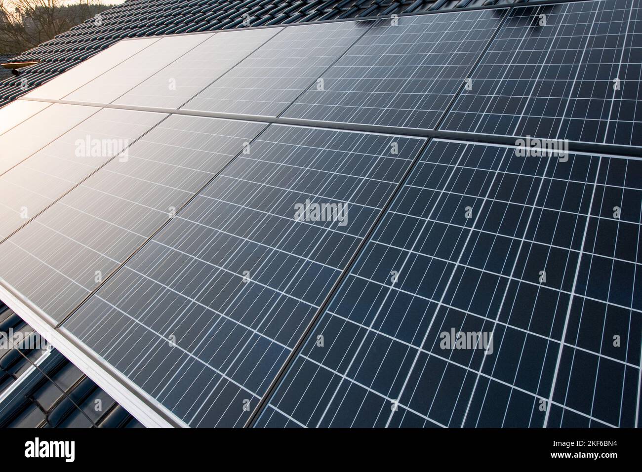 New solar panels are mounted on a roof with shiny black tiles and the ...