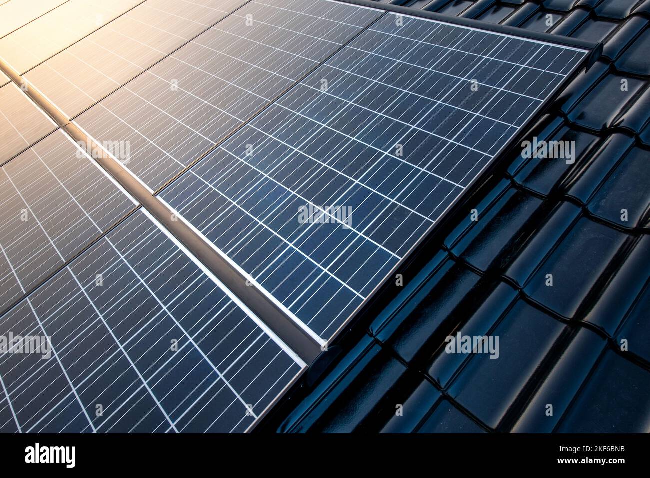 New solar panels are mounted on a roof with shiny black tiles and the ...