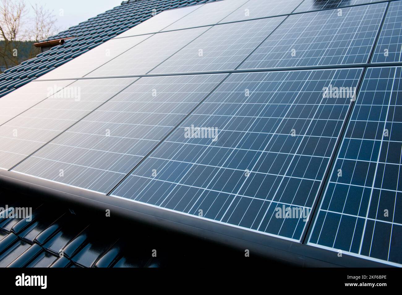 New solar panels are mounted on a roof with shiny black tiles and the ...
