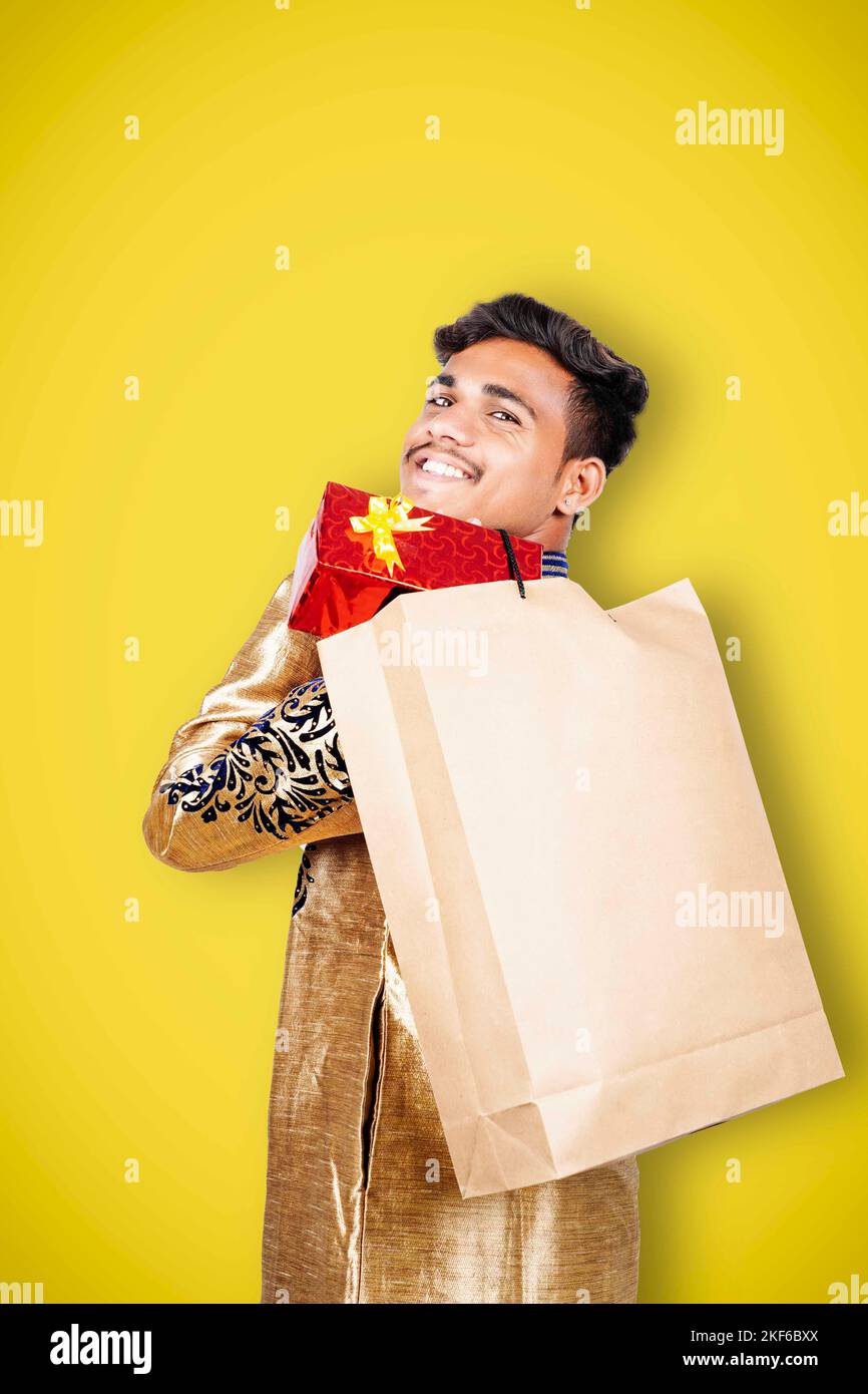 Indian man in ethnic wear with shopping bags and gift box, isolated ...