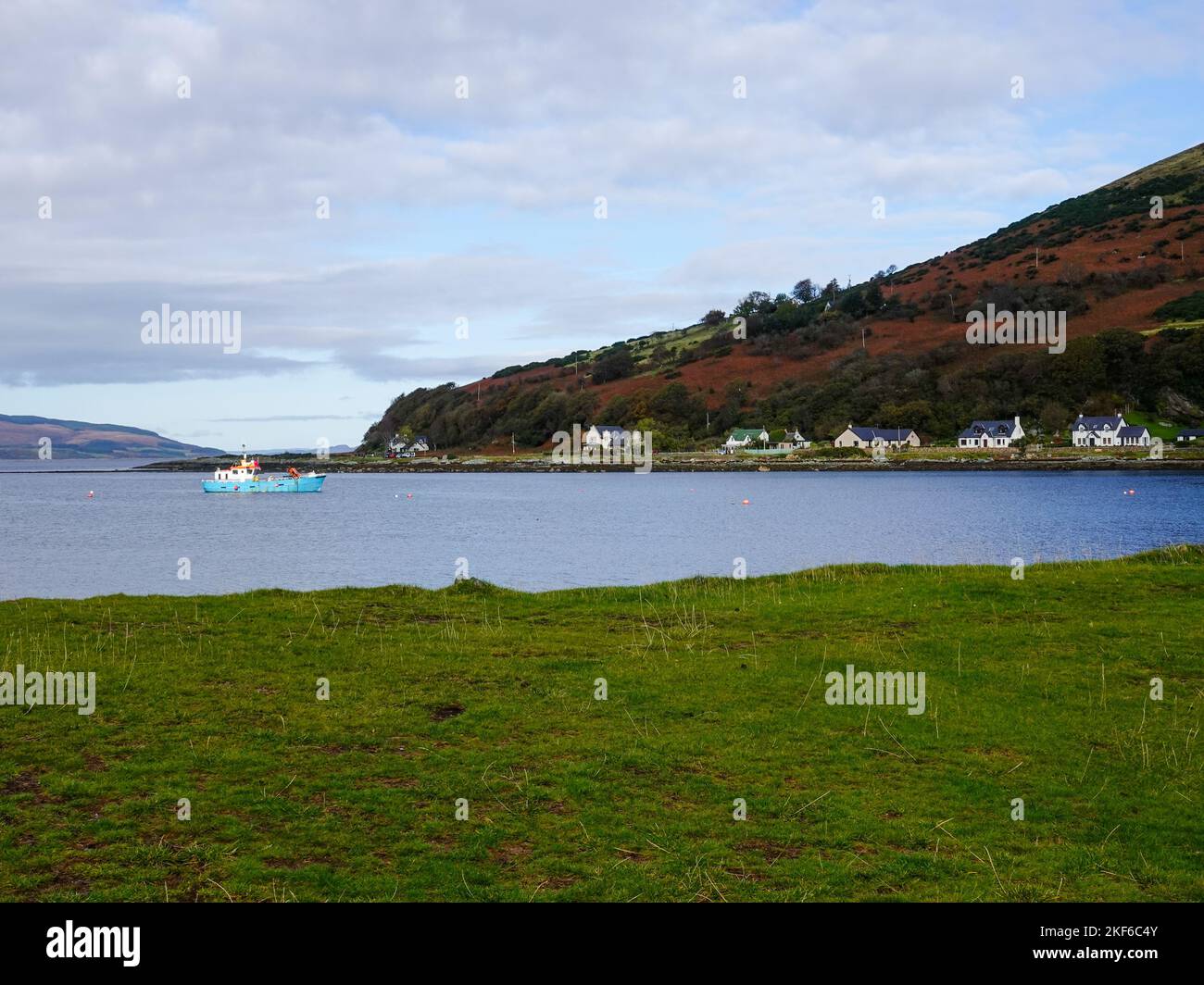 Working boat in harbour and cottages along the shore of Loch Ranza, a ...