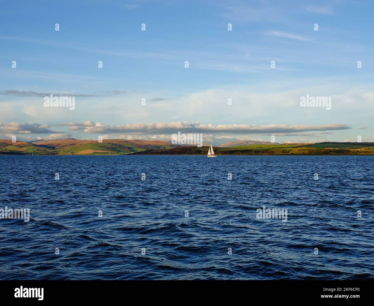 Sailboat off the Scottish coast landscape with rolling hills, Firth of ...