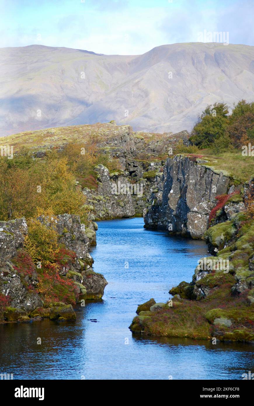 A vertical shot of calm river with the rocky shore against the ...