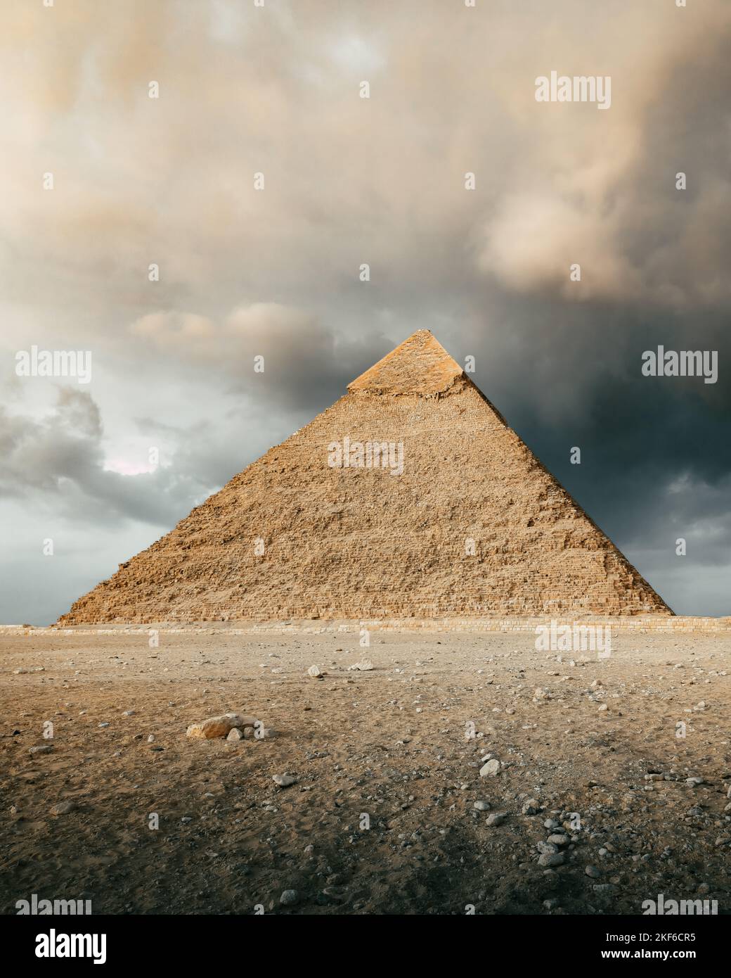 A vertical shot of the Great Pyramid of Giza with fluffy clouds in the ...