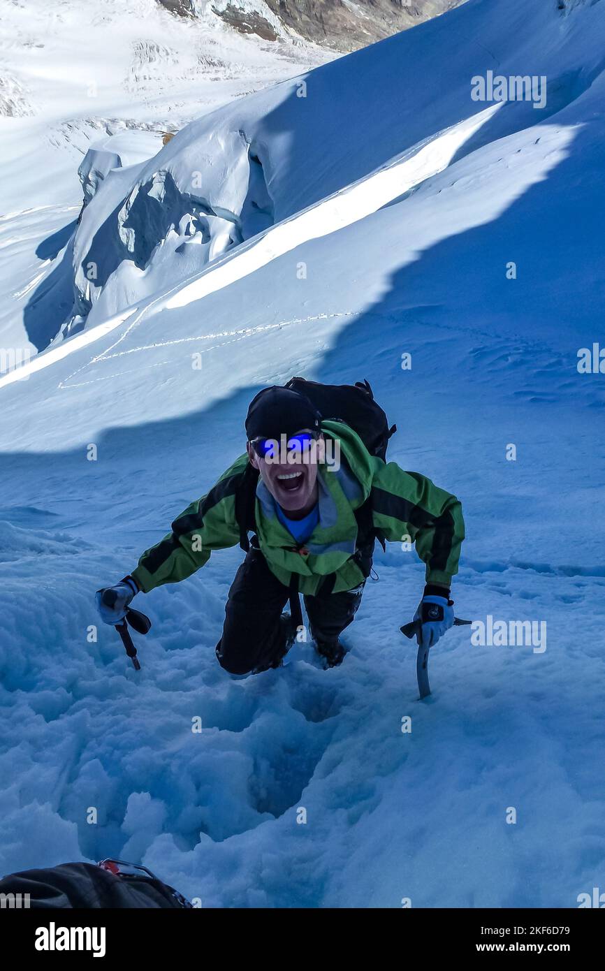 Description: Enthusiastic mountaineer climbing with ice axes over a ...