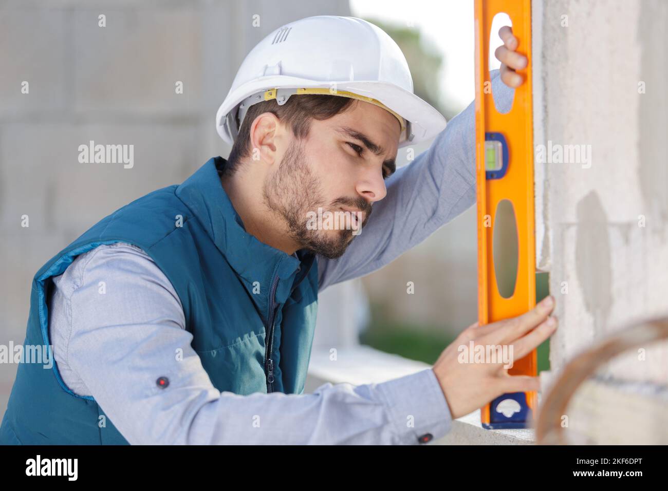 handsome young laborer measuring wall with level tool Stock Photo - Alamy