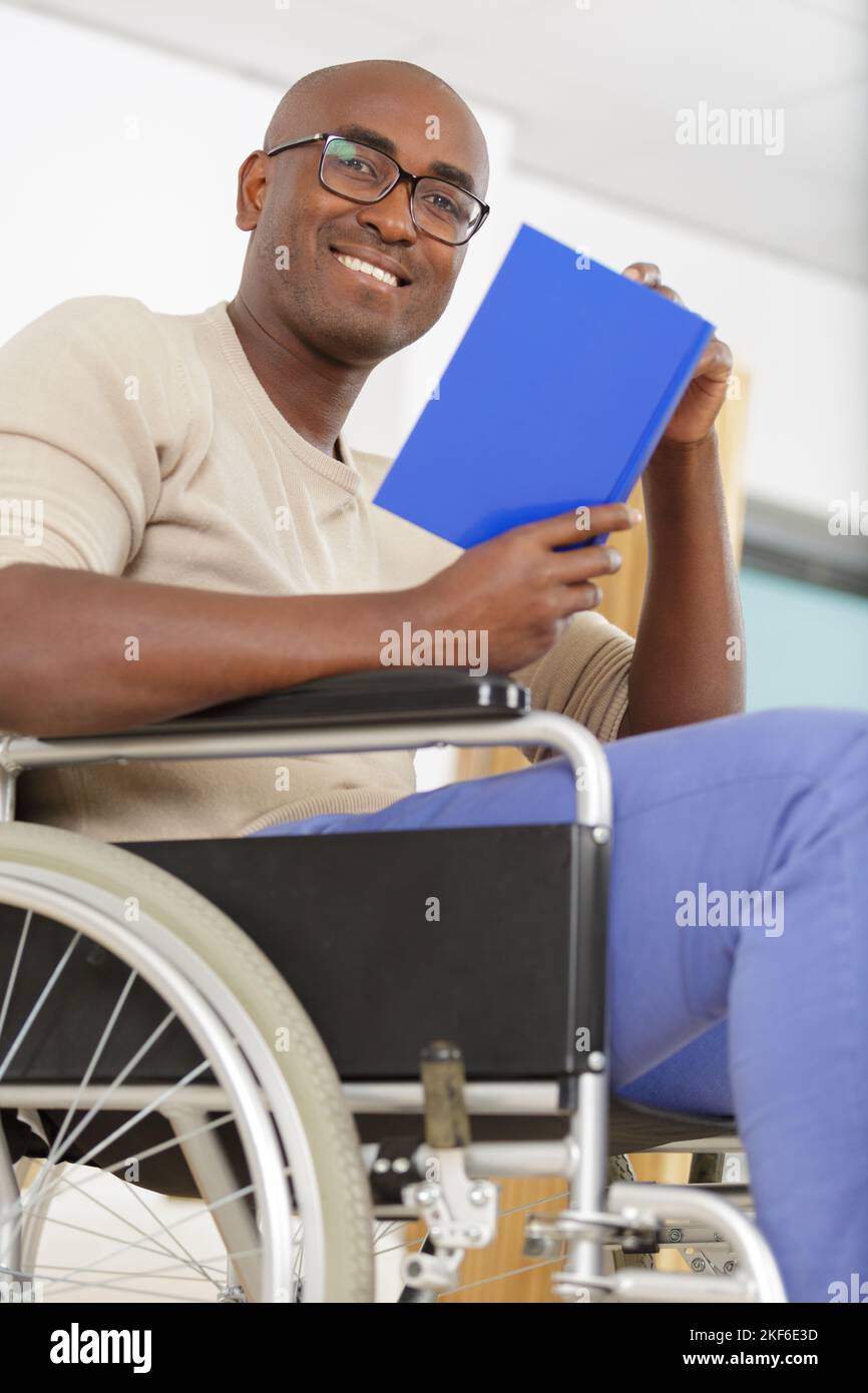 smiling physically handicapped man on wheelchair with book Stock Photo ...