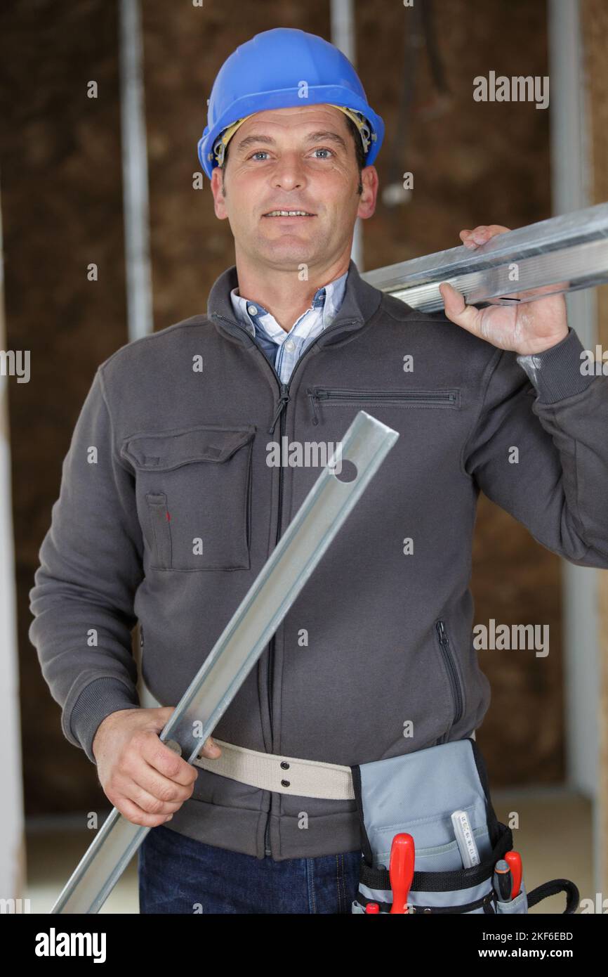 smiling construction worker carrying a metal bars Stock Photo - Alamy