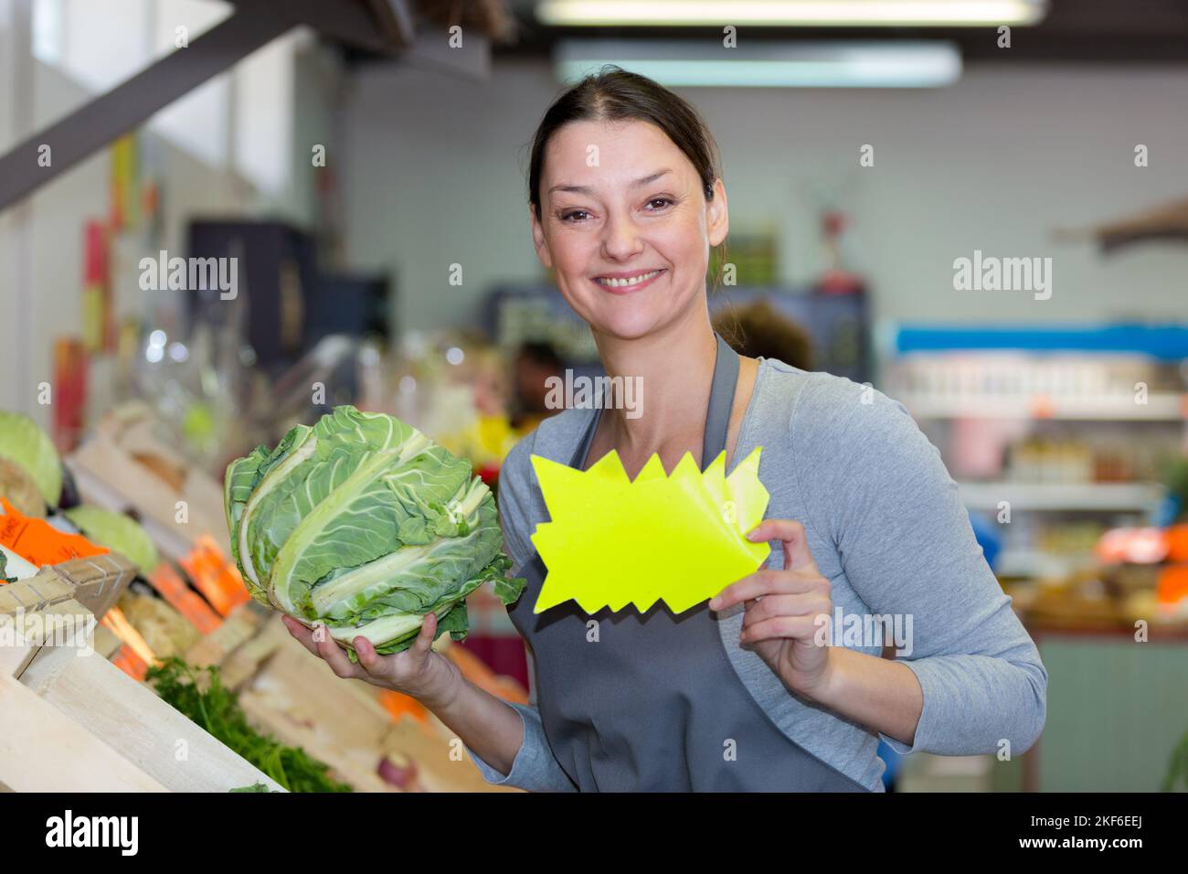 happy young shop assistant holding a board and cauliflower Stock Photo ...