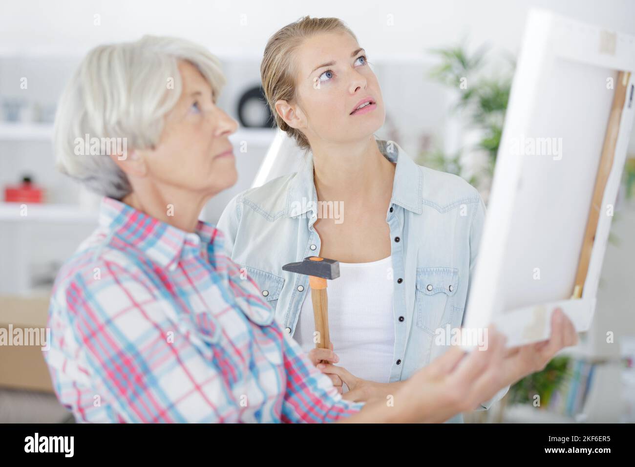 women fitting a frame on the wall Stock Photo - Alamy