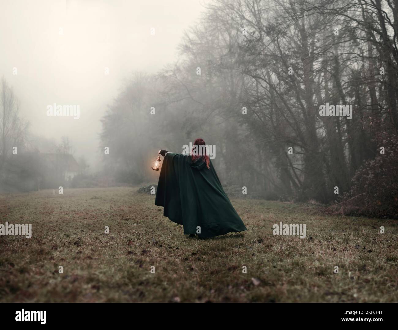 A young woman in the mist wearing a green cloak and holding a lit ...