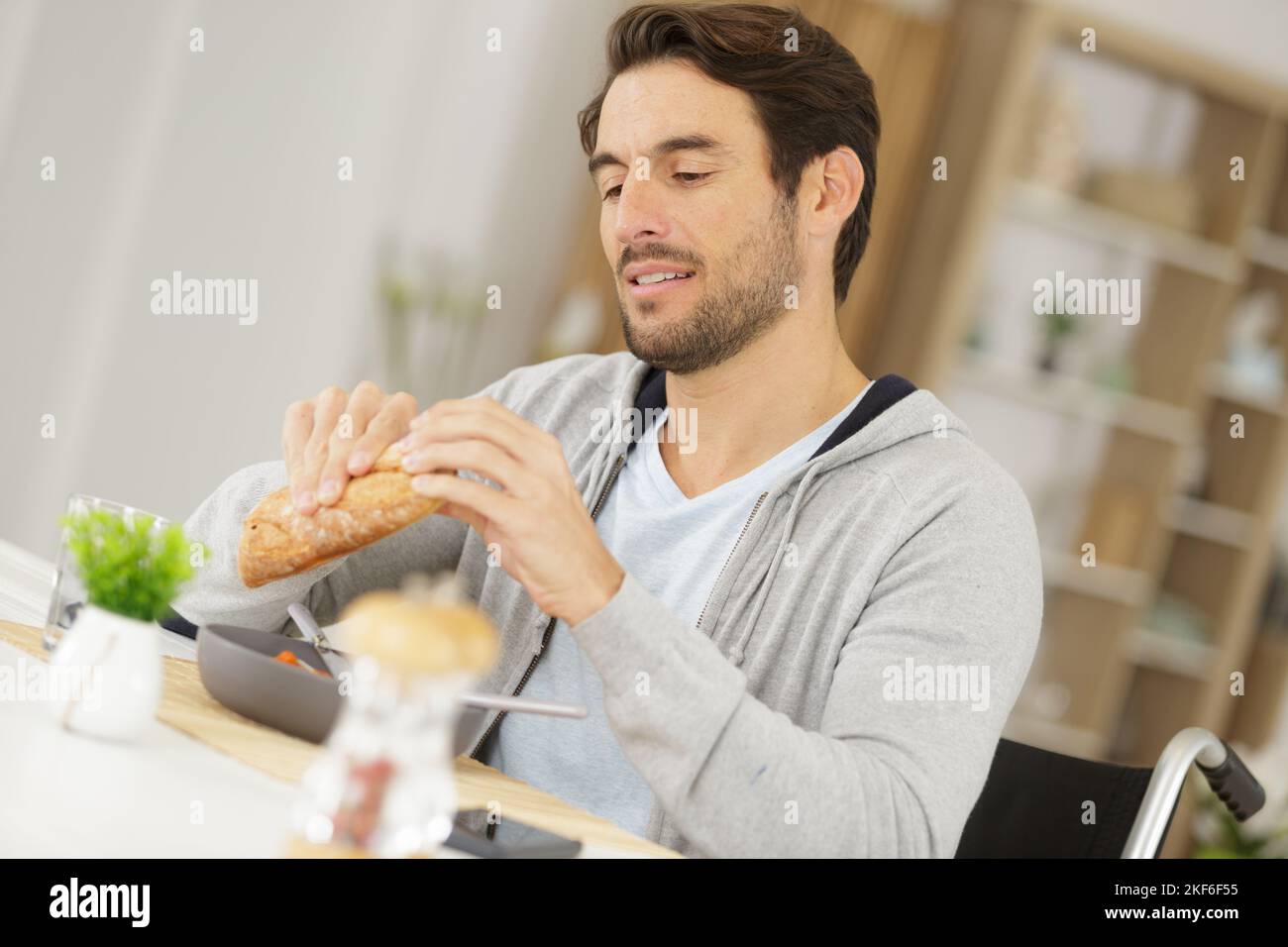 man in wheelchair breaking bread for his lunch Stock Photo - Alamy