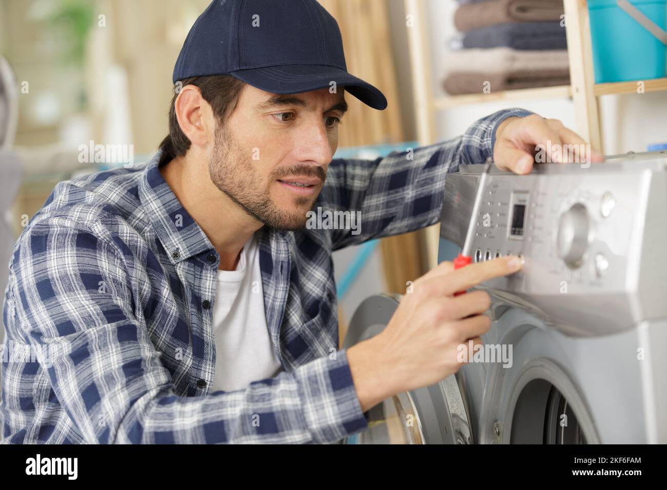 Plumber in uniform is fixing a washing machine hi-res stock photography ...