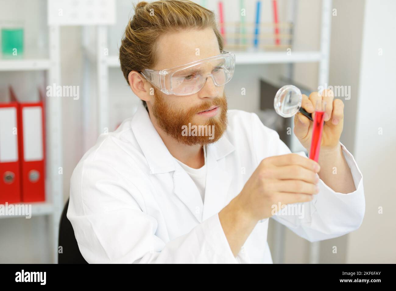 male scientist analysing something through a magnifying glass Stock ...