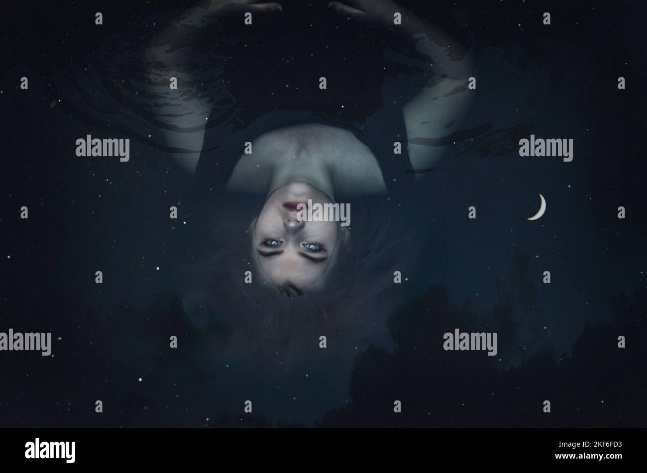 Young woman floating in water that reflects a starry night sky and the ...