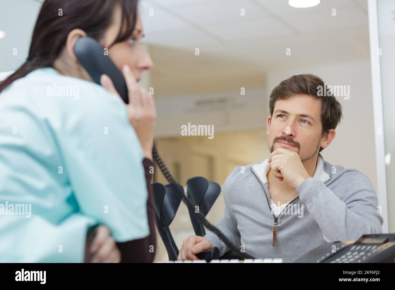 receptionist and doctor with client in hospital Stock Photo - Alamy