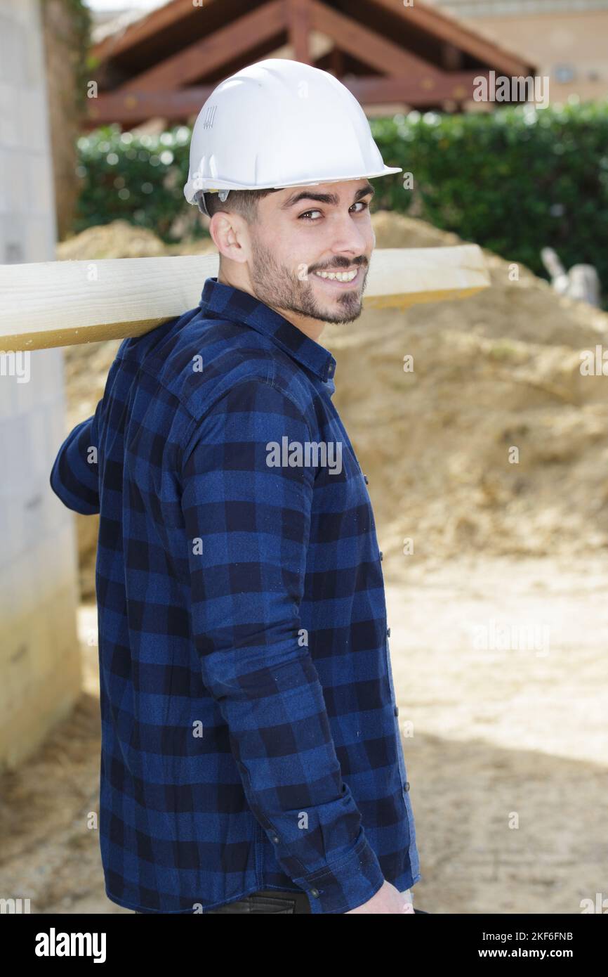construction worker carrying wood on his shoulder Stock Photo - Alamy