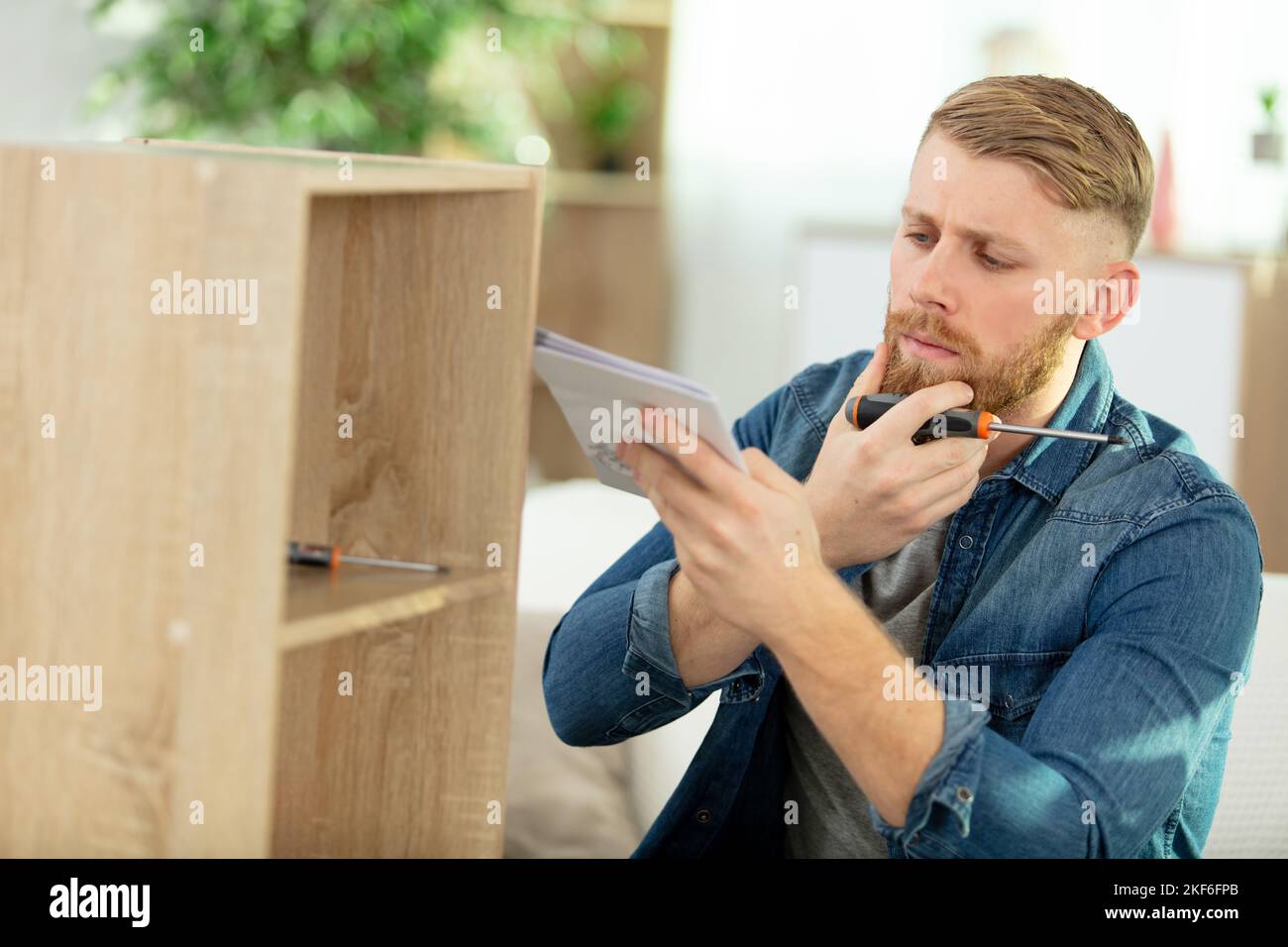 the young man tries himself to fold his bookcase Stock Photo - Alamy
