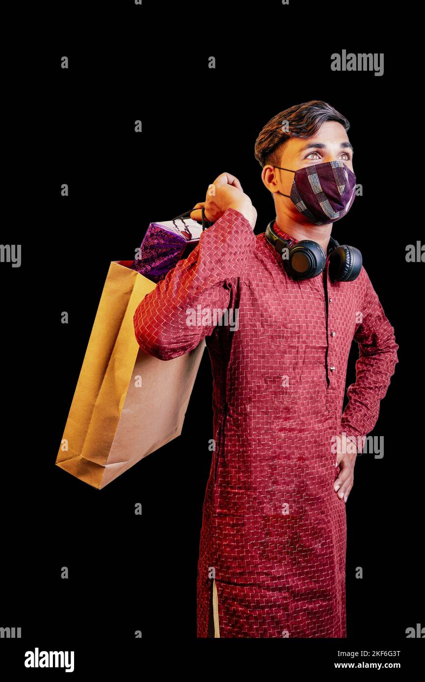 Indian man in ethnic wear and mask with shopping bags, isolated over ...