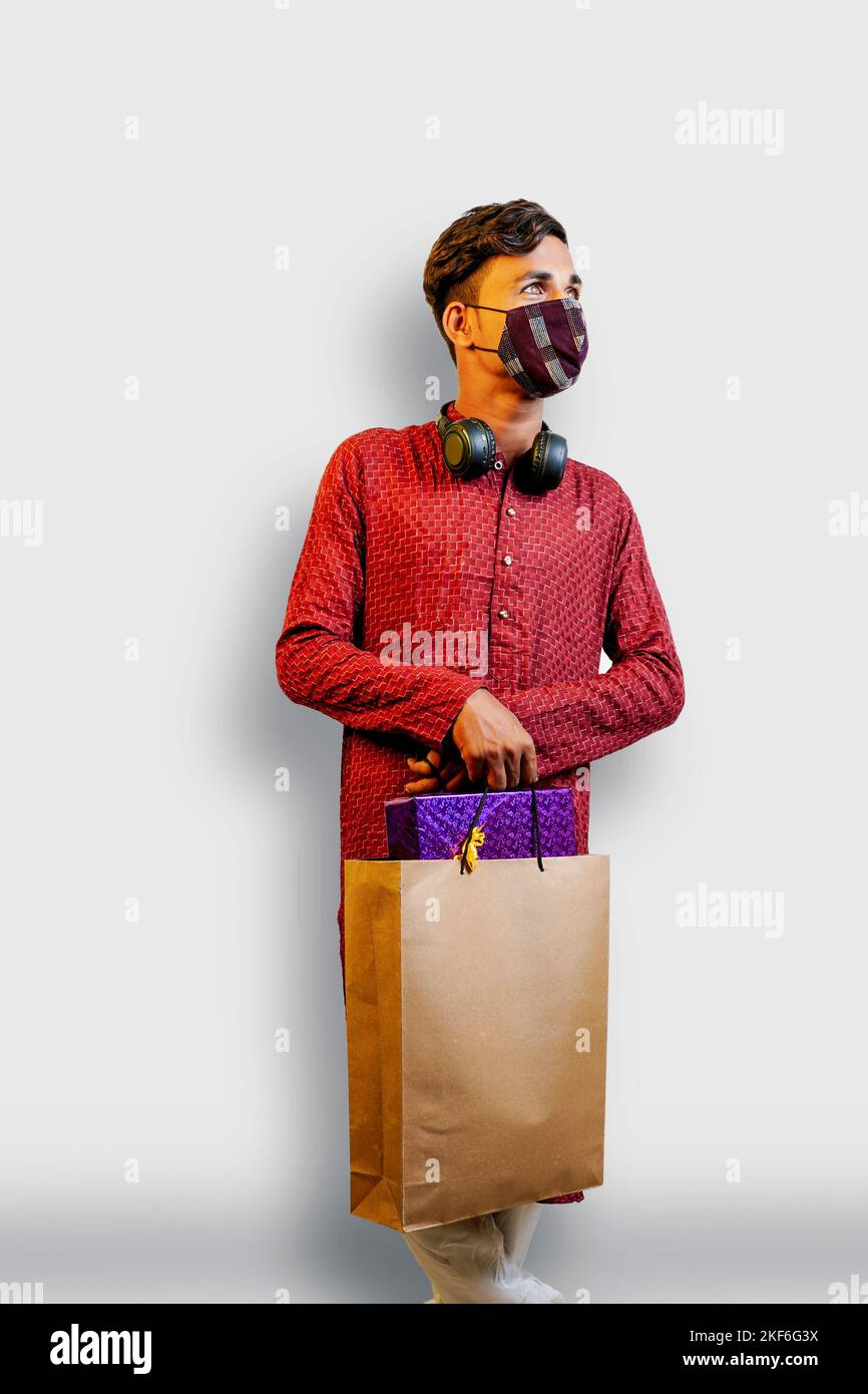 Indian man in ethnic wear and mask with shopping bags, isolated over ...