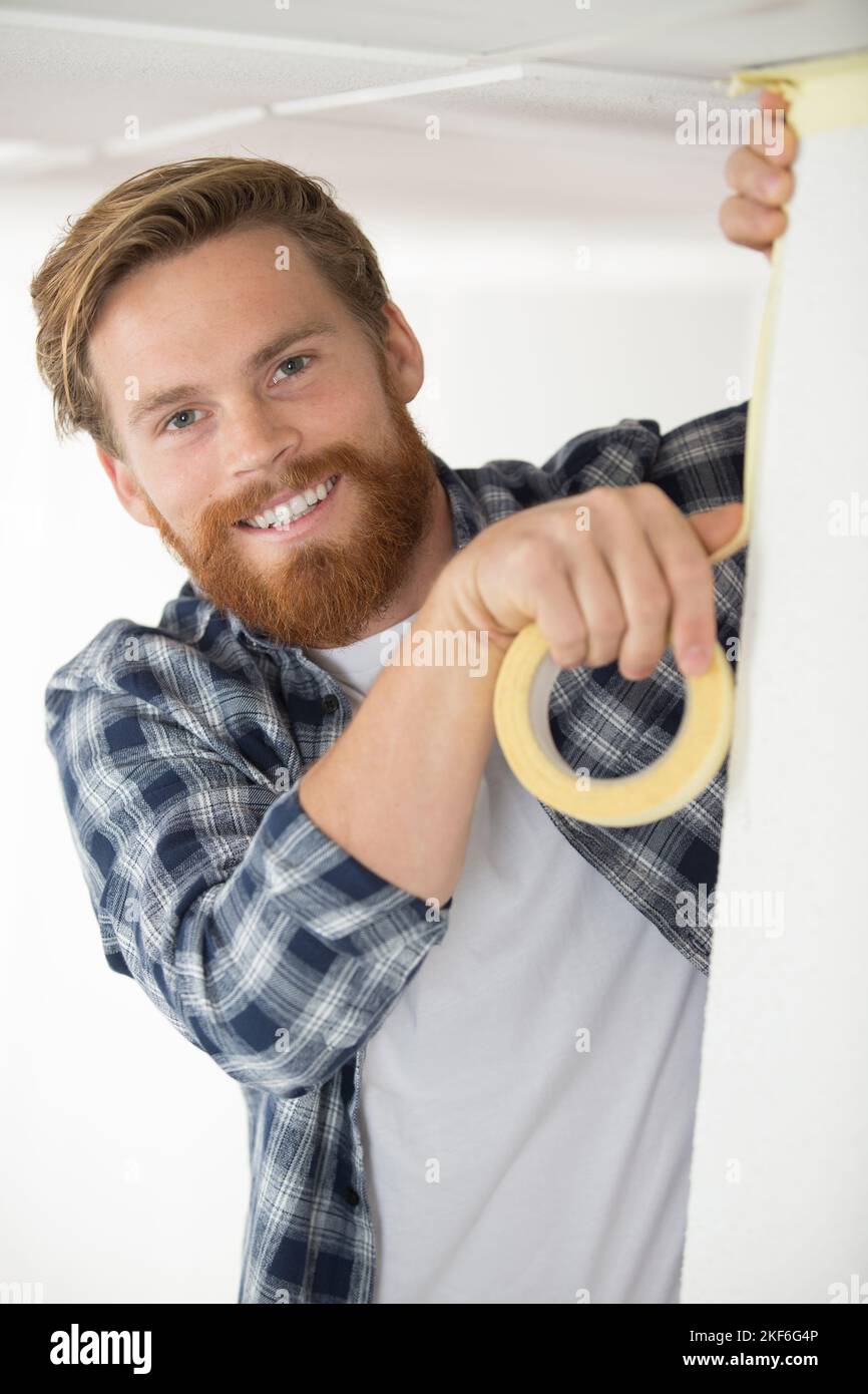 smiling man applying masking tape while redecorating Stock Photo - Alamy