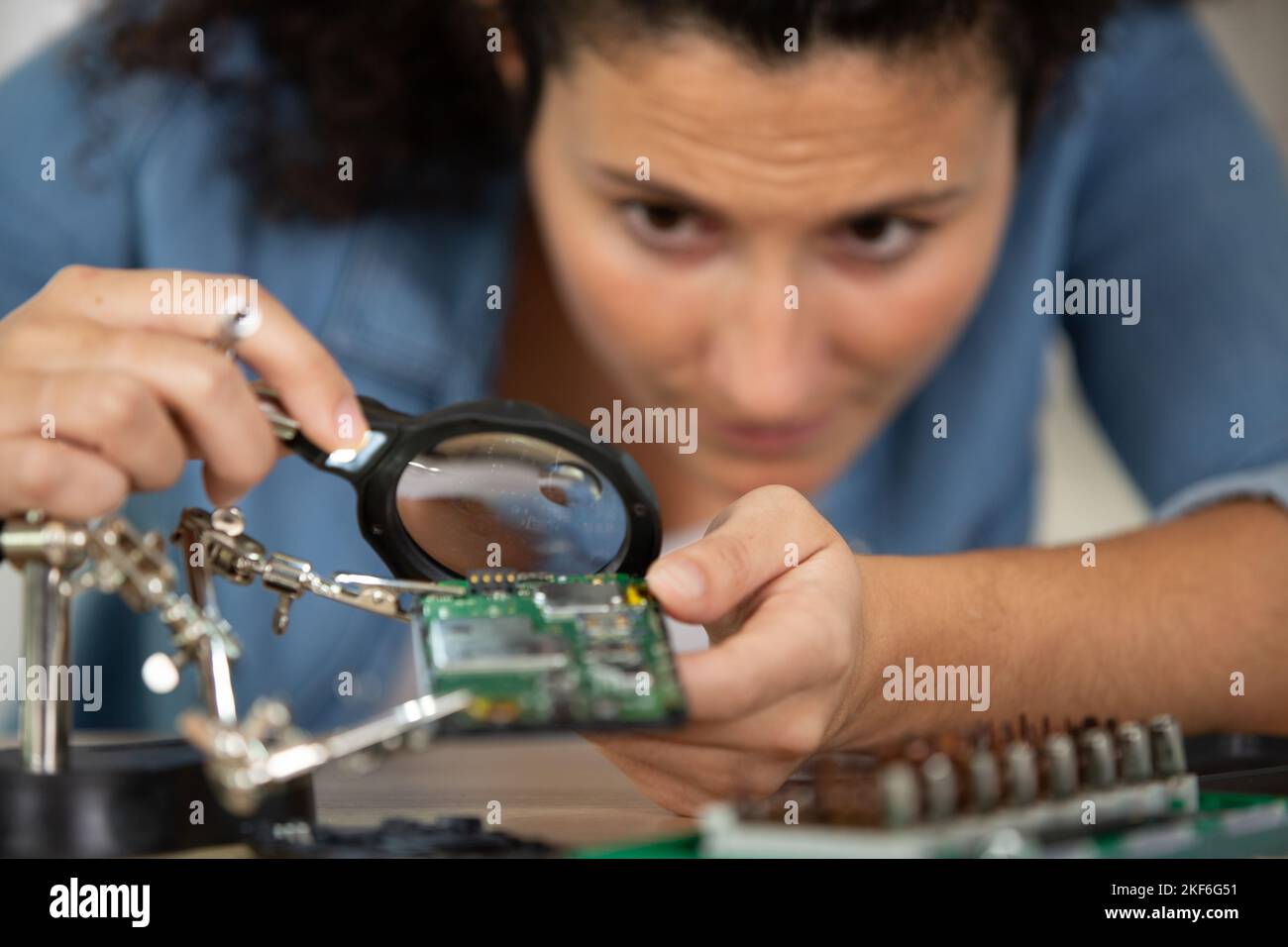 it woman using magnifying glass fixes computer hardware Stock Photo - Alamy