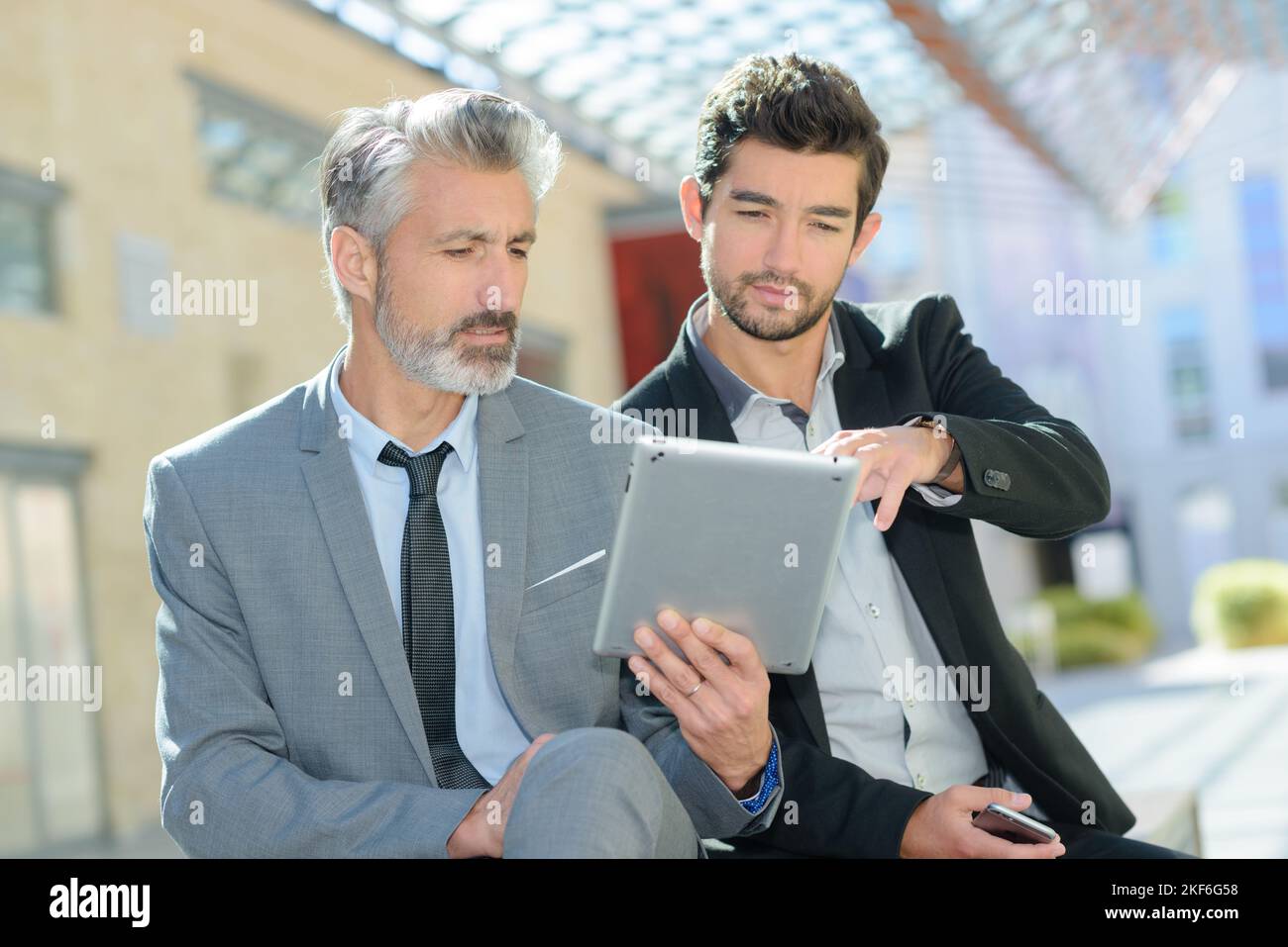 two suited men looking at digital tablet Stock Photo - Alamy