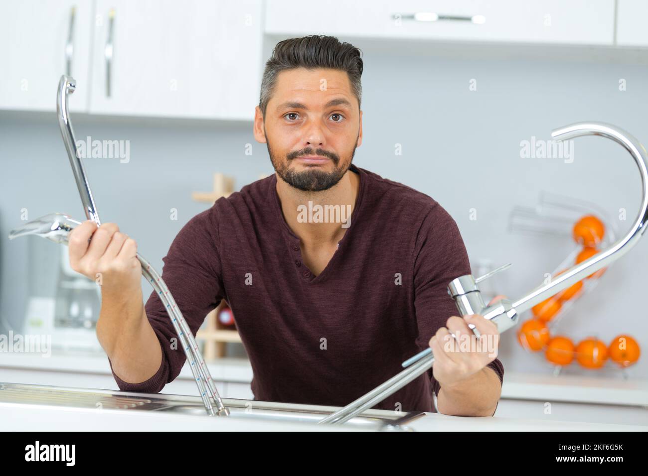 plumber working on a broken tap in the kitchen Stock Photo - Alamy