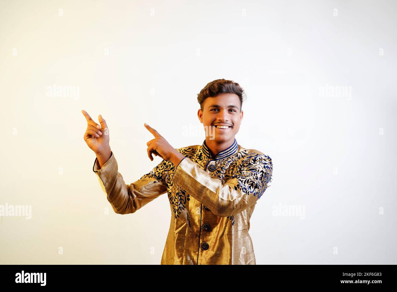 young Indian man in ethnic wear and showing direction with hand or ...
