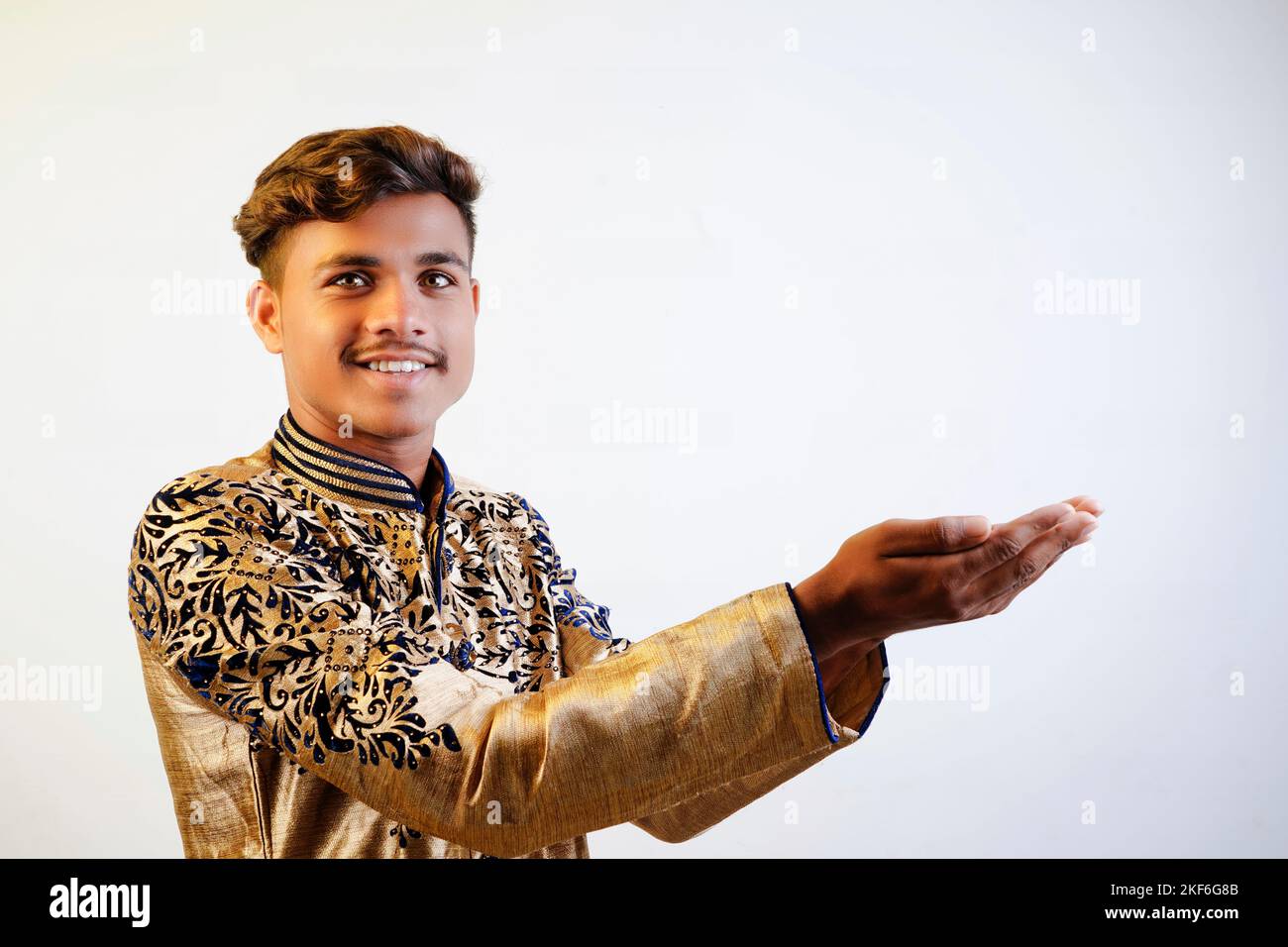 young indian man in traditional wear showing thumb, hand, empty hands ...