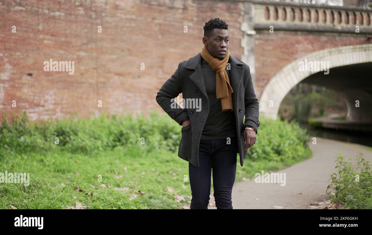 Black man walking outside during winter season putting on gloves ...