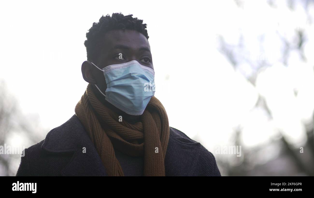 Black man wearing covid face mask walking outside in city downtown ...