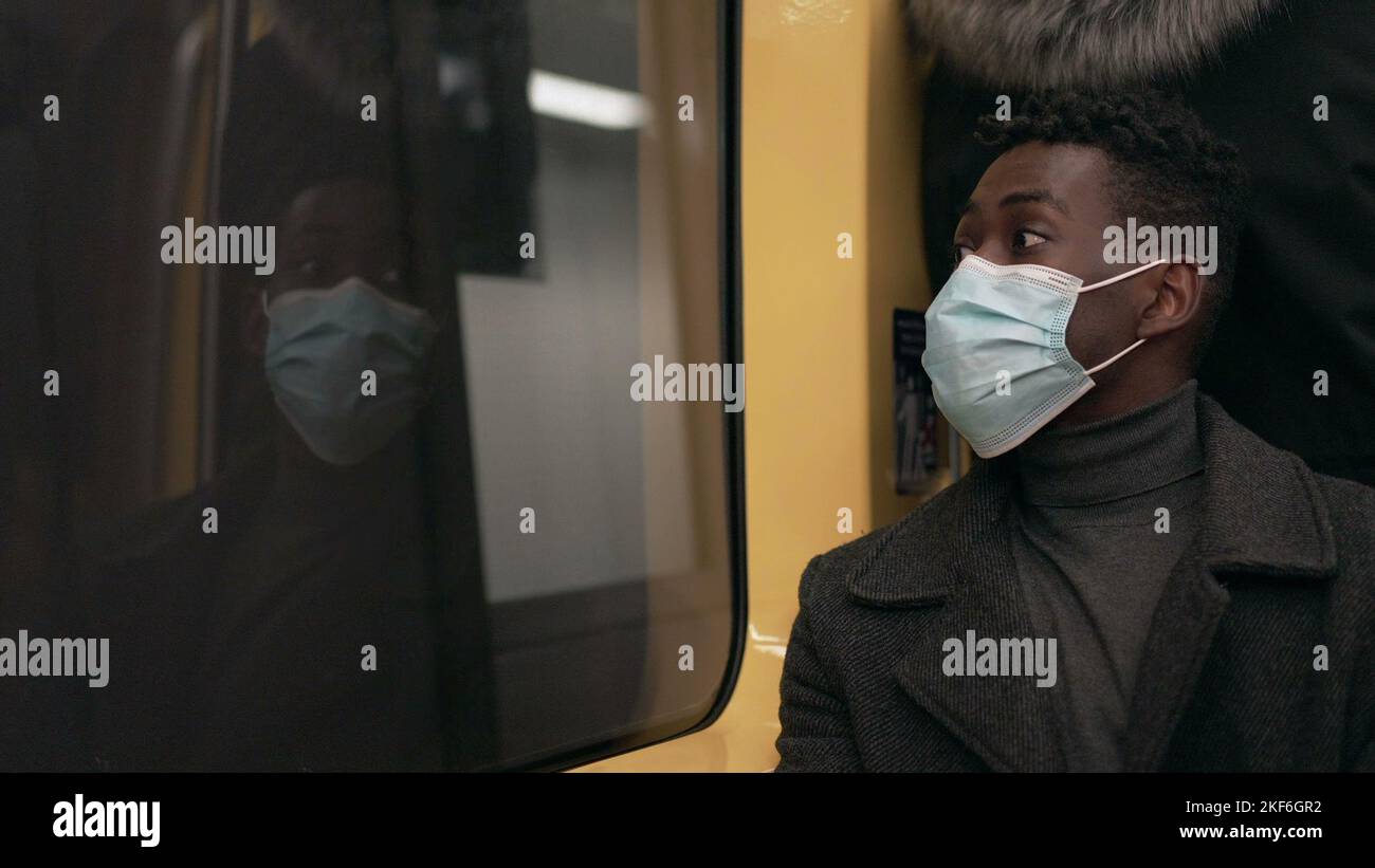 Black man wearing covid surgical face mask while riding metro subway ...