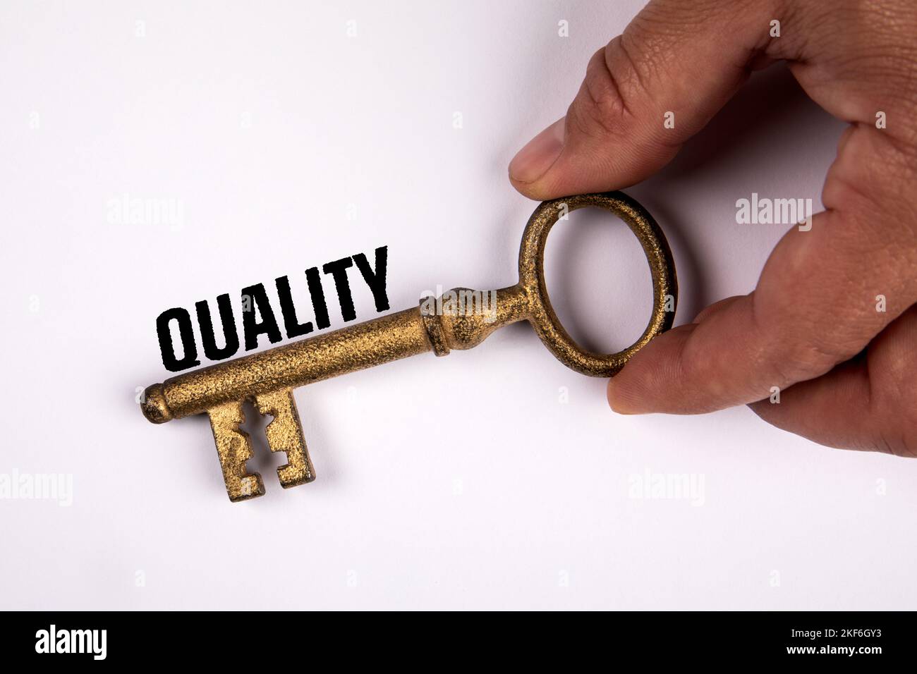 Quality, success and knowledge concept. Golden key on a white ...
