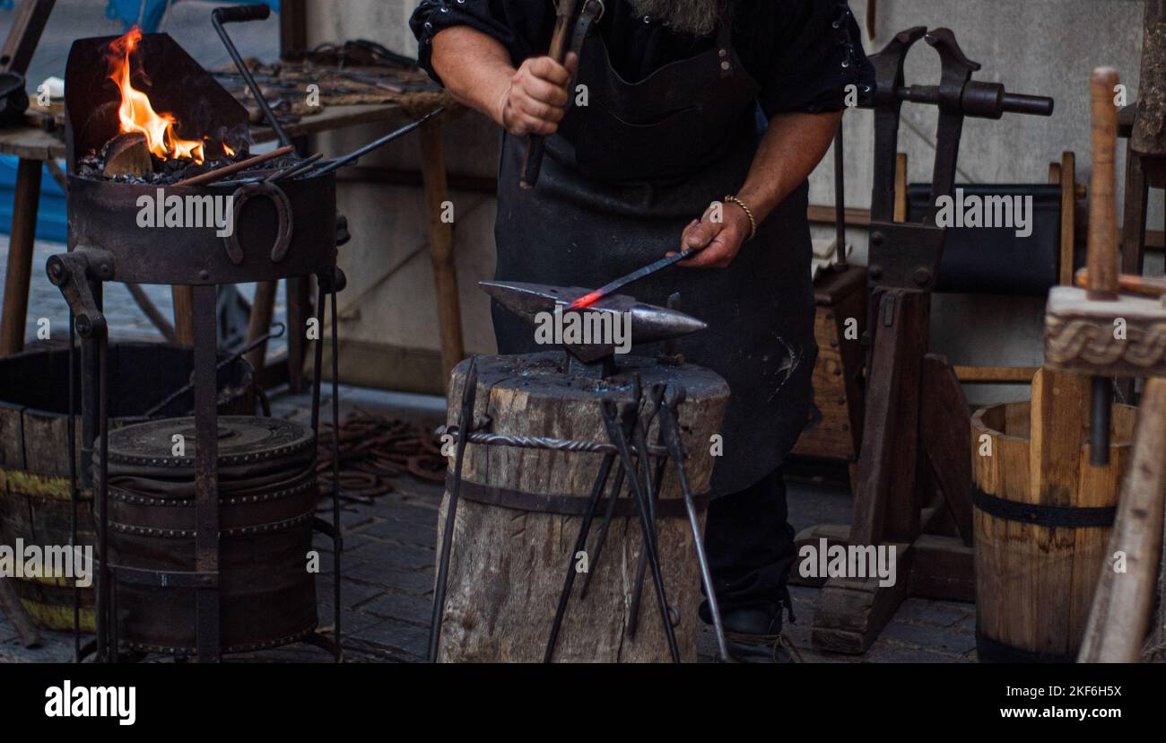 The partial view of a blacksmith shaping the hot metal in his smithy ...