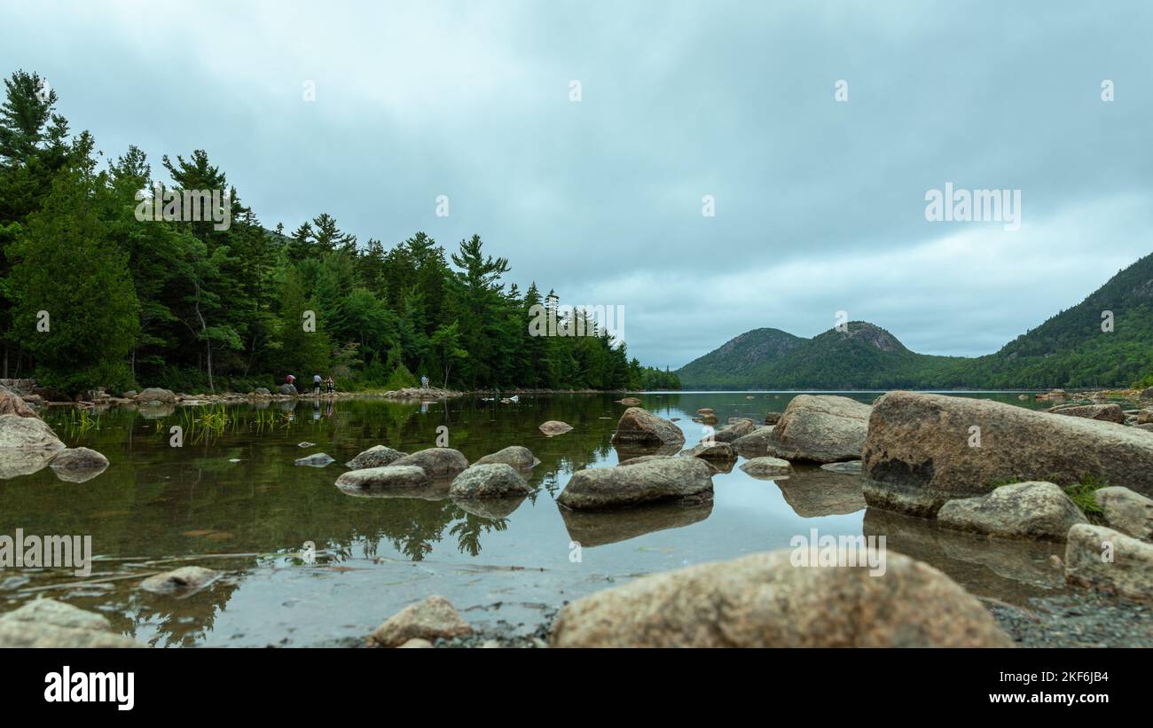 A beautiful view of Jordan Pond in mountains against a green forest ...