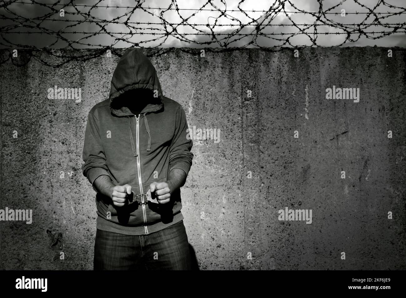 The criminal stands in front of the prison wall with barbed wire. Law ...