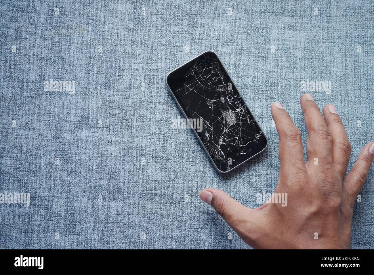 hand reaching from a broken smart phone on table Stock Photo - Alamy