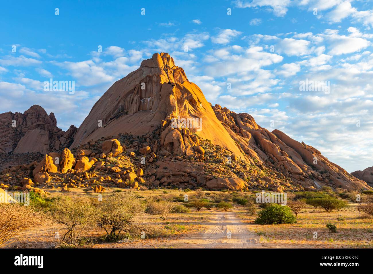 Red granite rock colored yellow on one side by rising sun Spitzkoppe ...