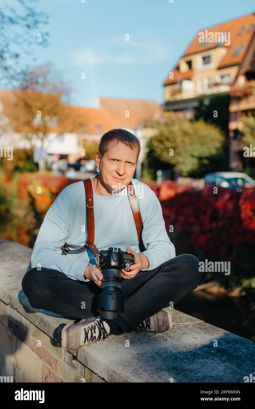 Man Sitting in Old European City And Holding Photo Camera. Contemporary ...