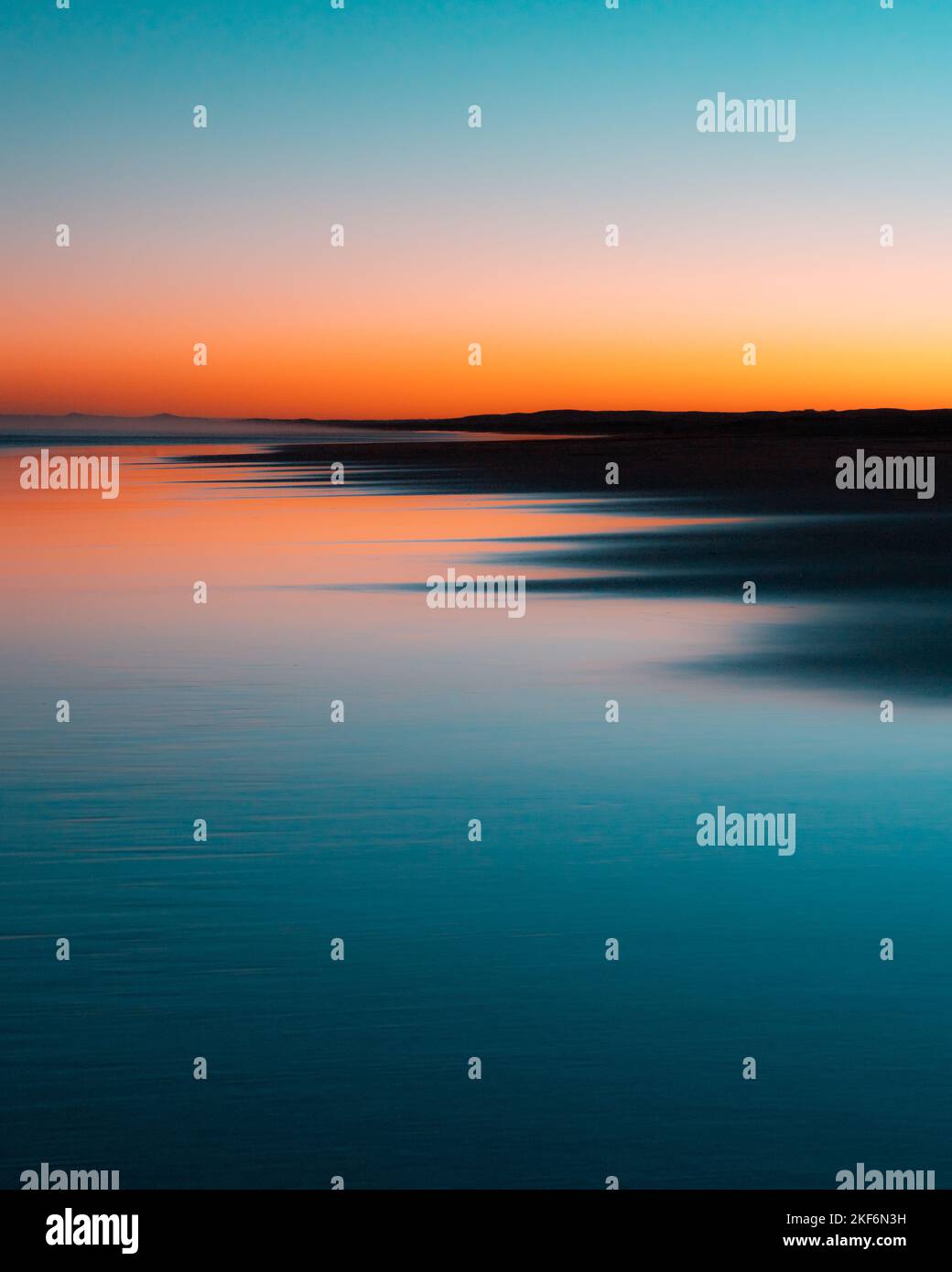 A vertical shot of a gradient sky during sunset perfectly reflecting on ...