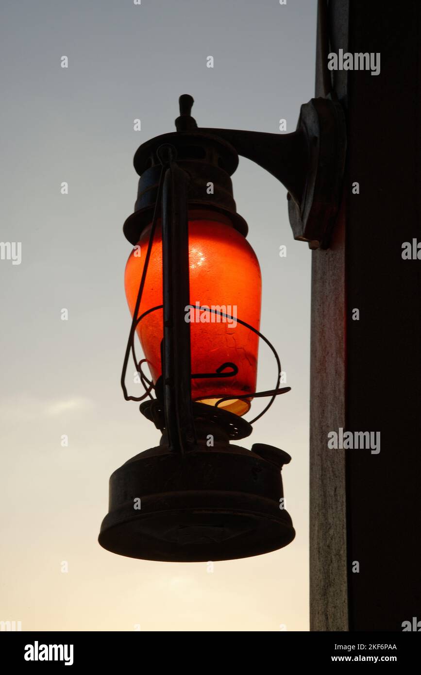 A red filtered lantern hanging up. A lit lantern at dusk. A red ...