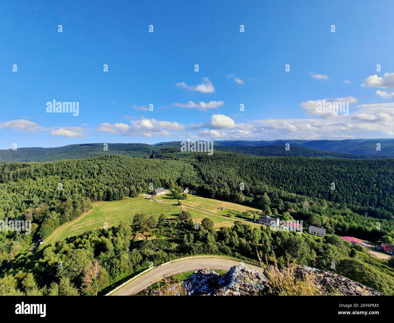 Stunning view of layered mountain ranges covered with dense forest, small village in green ...