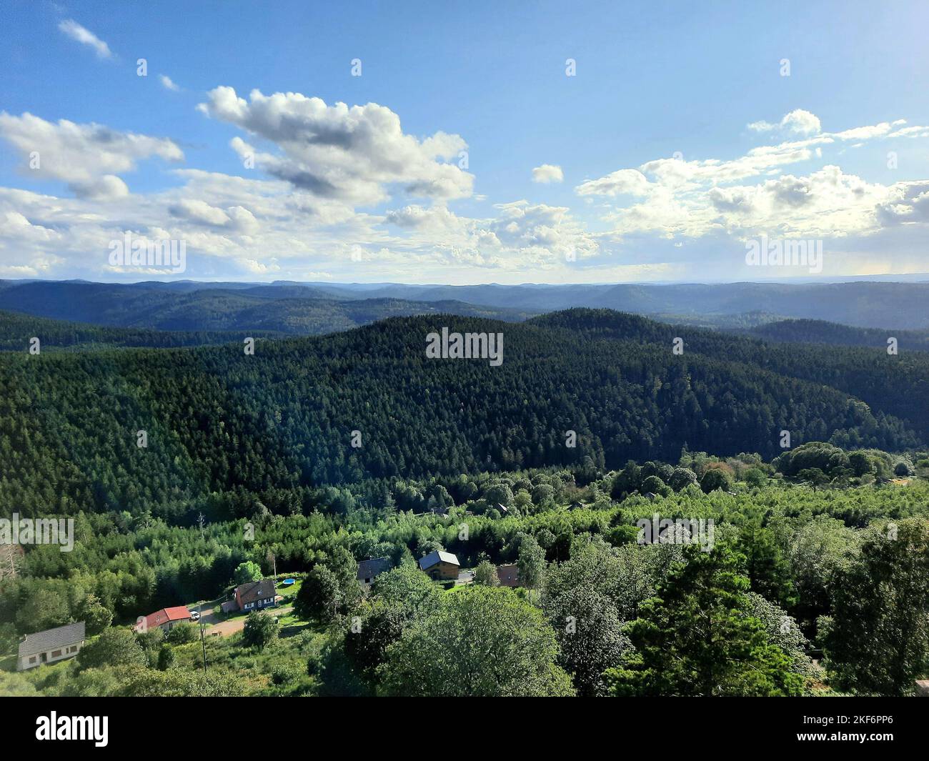 Stunning view of layered mountain ranges covered with dense pine forest and small village in ...