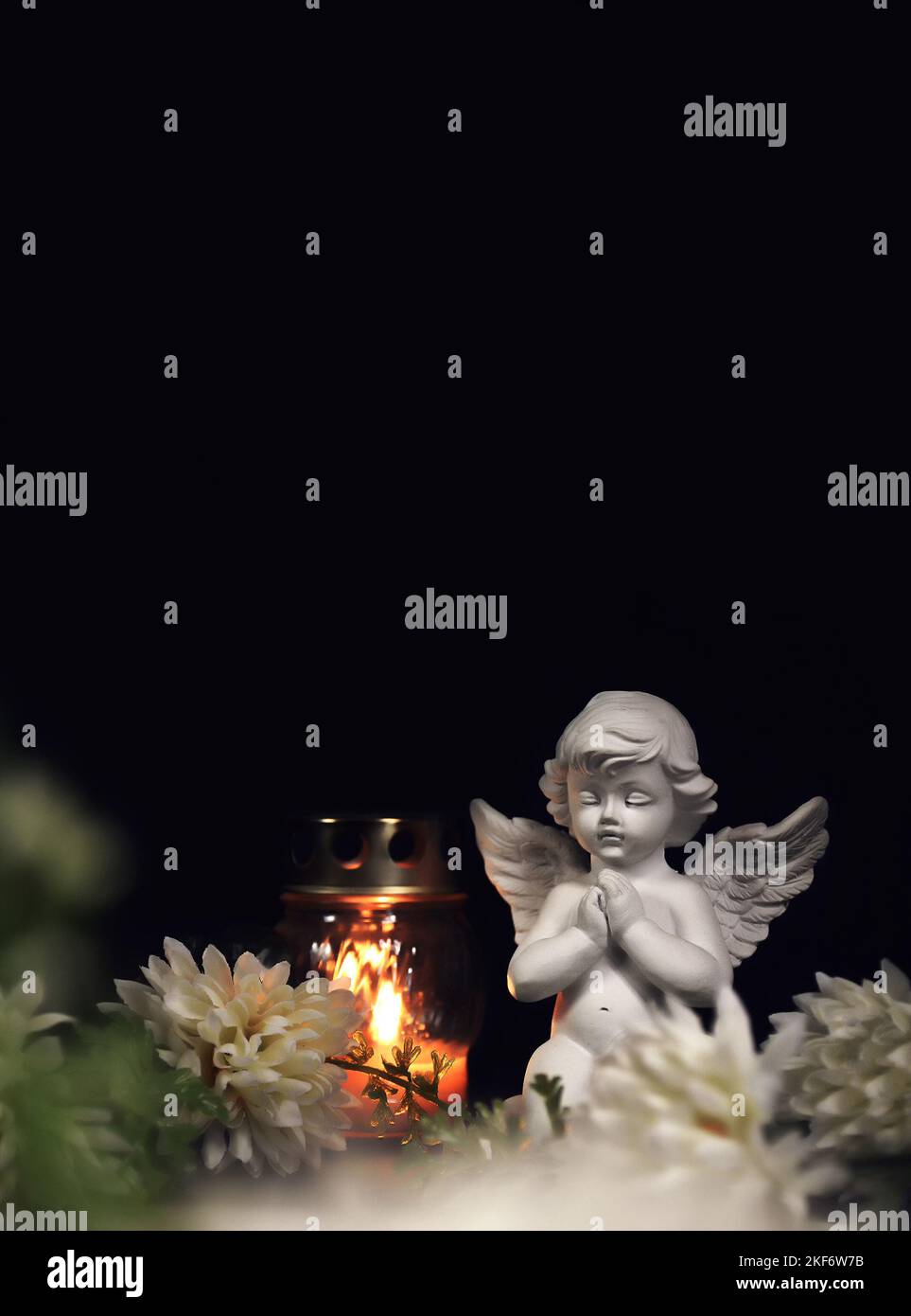 Funeral candle, flower and angel figurine on black background. Sympathy ...